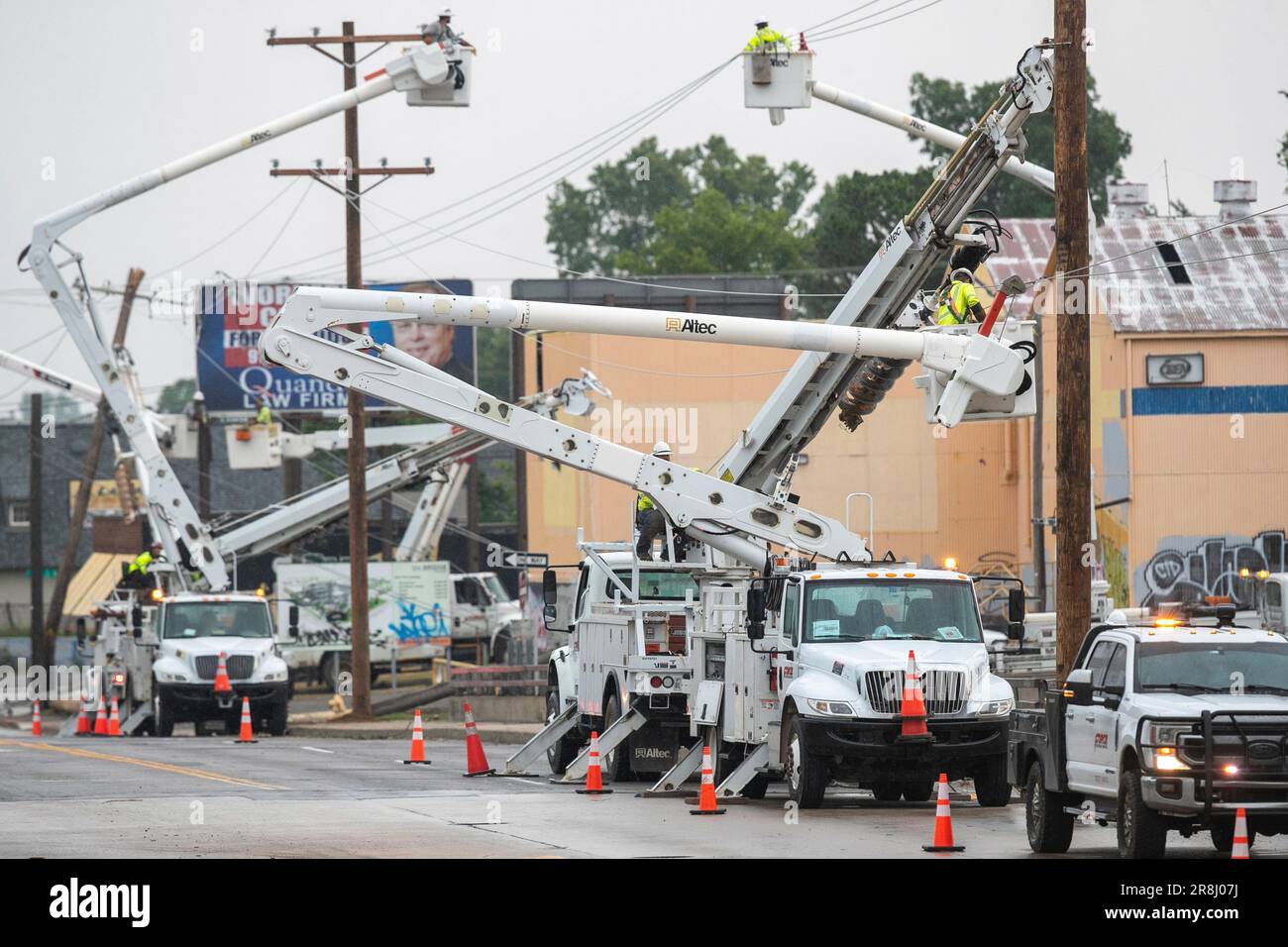 Line workers in boom trucks and on the street work to replace broken ...