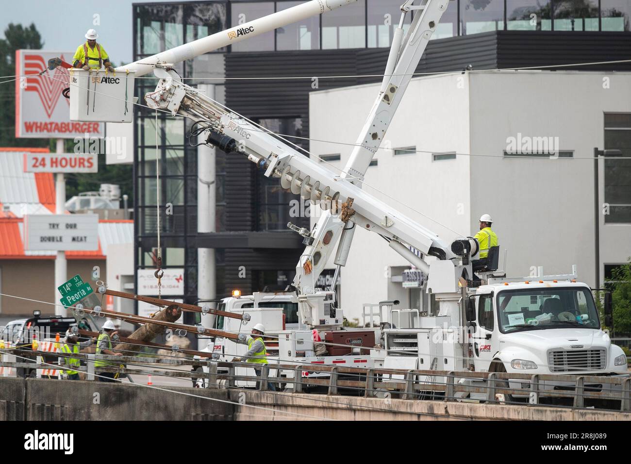 Line workers in boom trucks and on the street move a broken utility ...