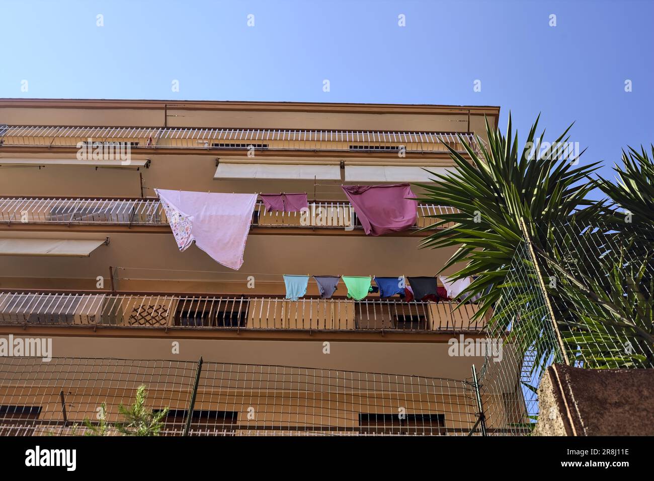 Balconies of a condominium with hanging clothes on a sunny day seen ...
