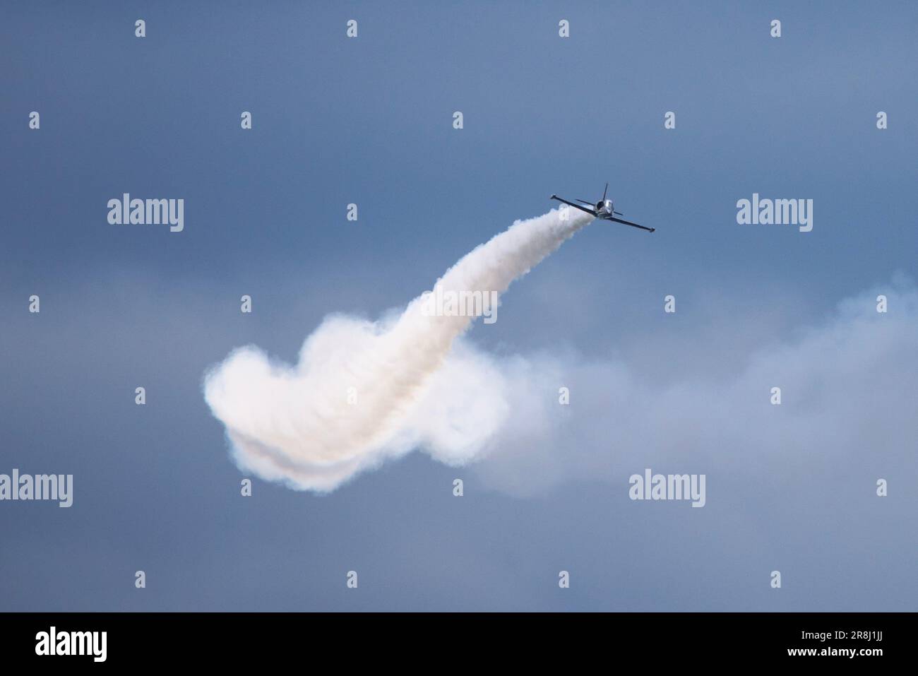 A single-engine airplane emitting a plume of white smoke from its tail ...