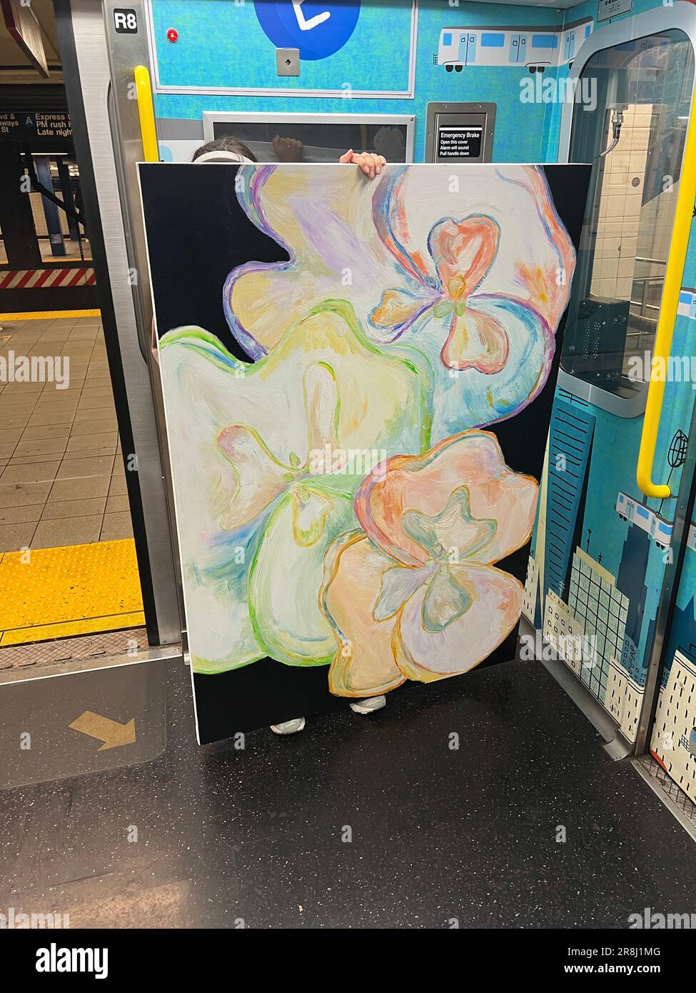 Woman transports a floral like painting on a subway train in Brooklyn ...