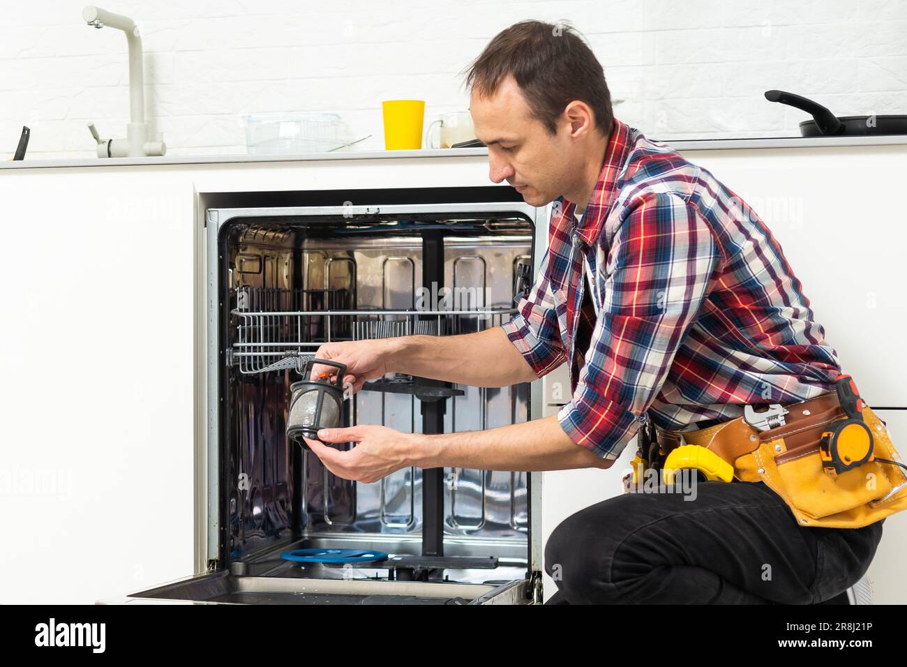 Worker repairing the dishwasher in the kitchen Stock Photo - Alamy