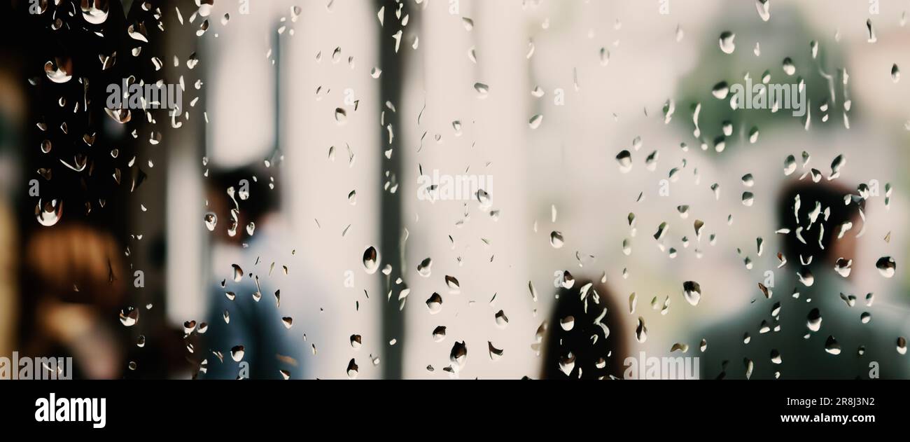 Rain drop on window glass of coffee shop and blurry city life ...