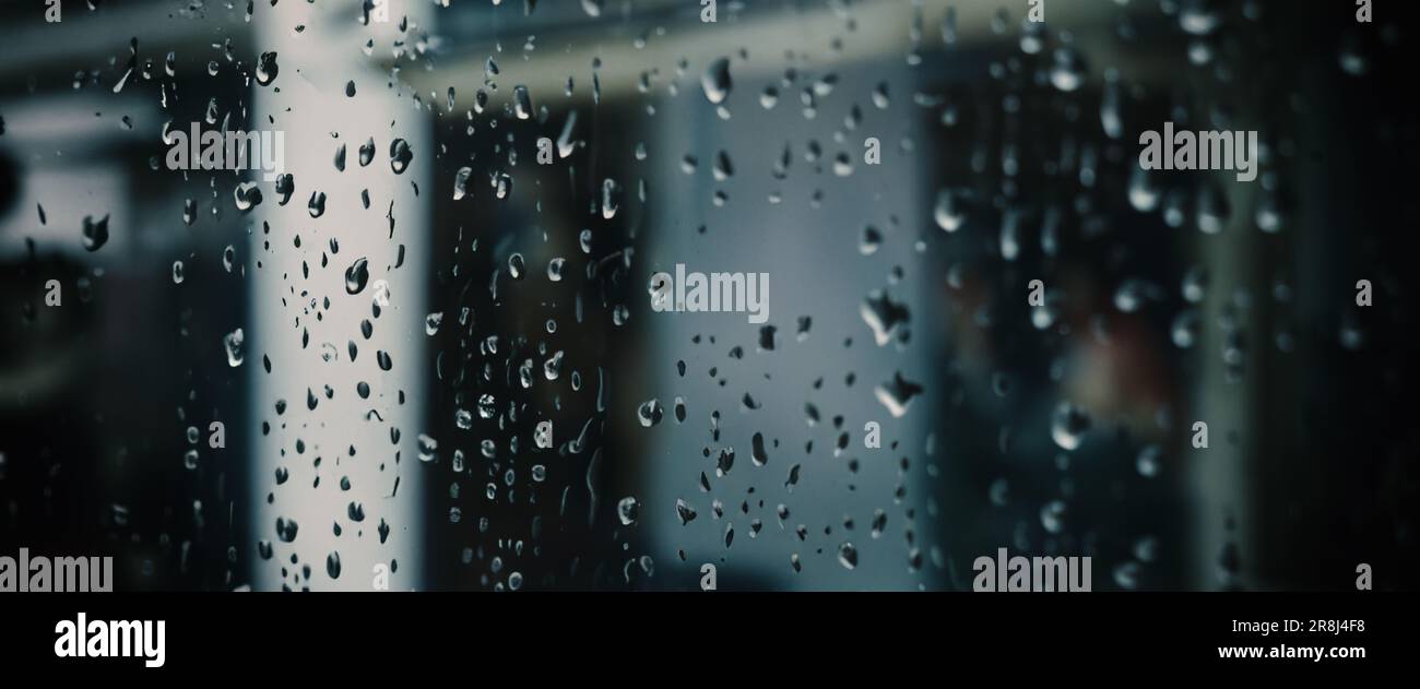 Rain drop on window glass of coffee shop and blurry city life ...