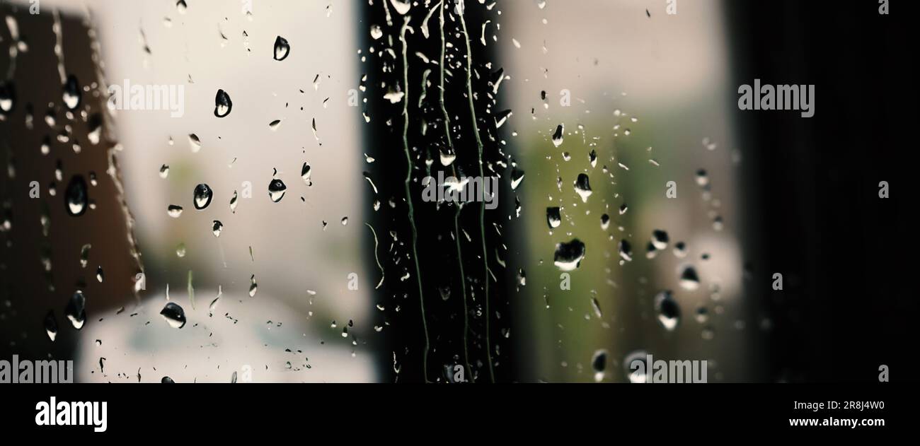 Rain drop on window glass of coffee shop and blurry city life ...