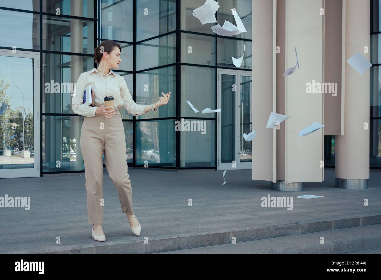Business woman runs out of an office building throwing paperwork around ...