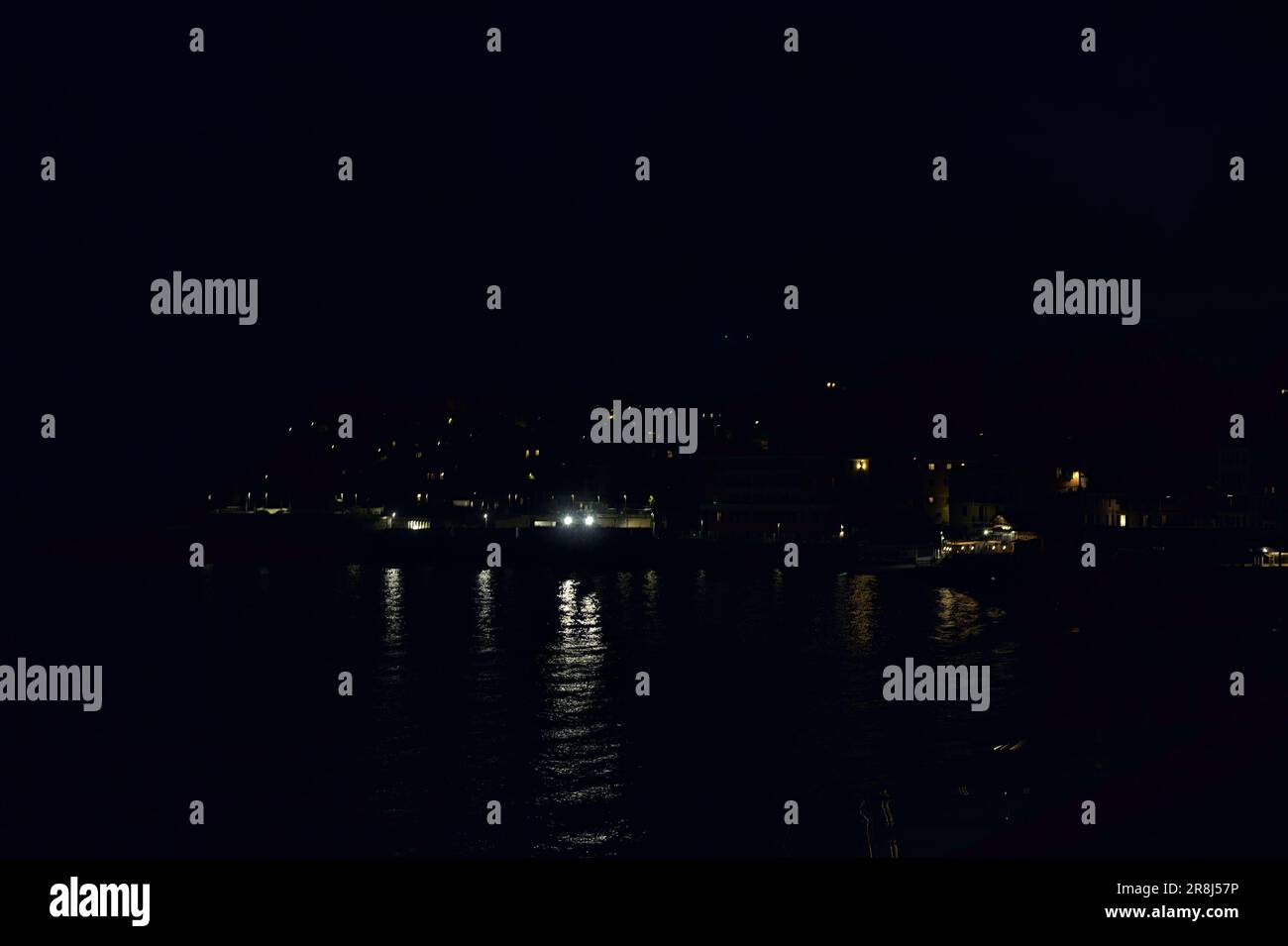 Town on a cliff by the sea at night seen from a beach afar Stock Photo ...
