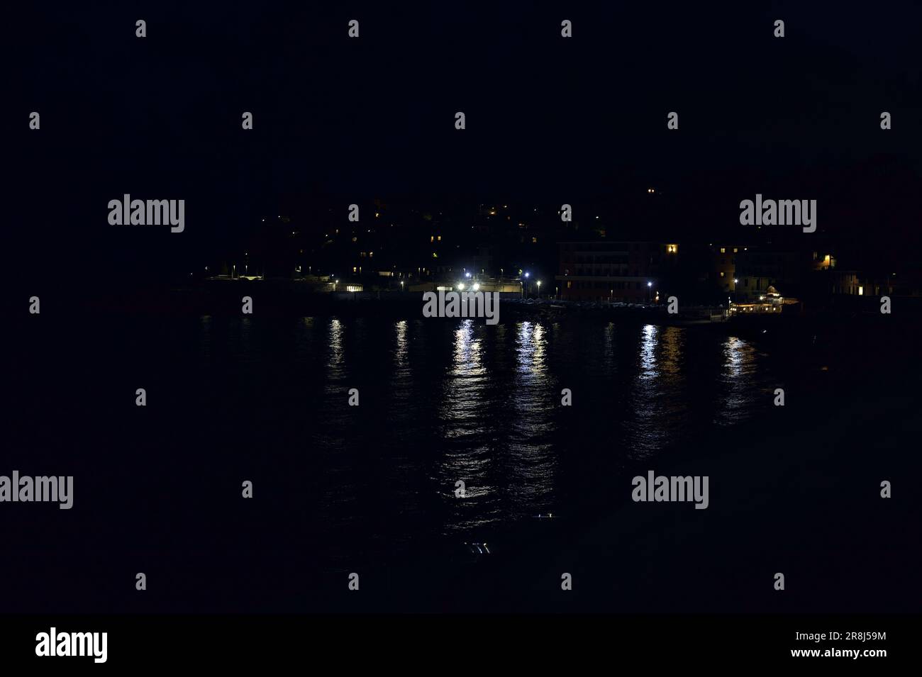 Town on a cliff by the sea at night seen from a beach afar Stock Photo ...
