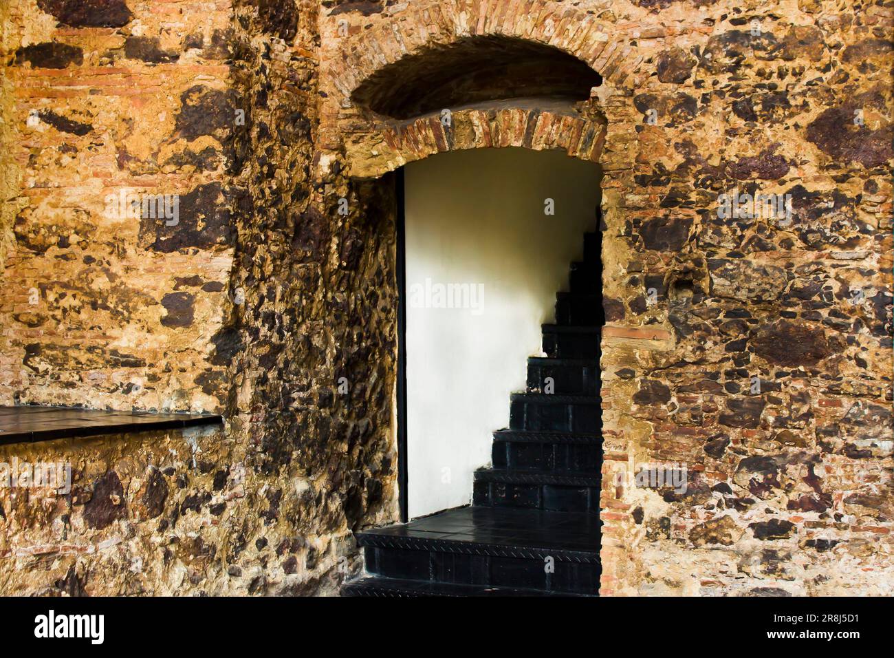 Background wall of antique stones with passage for black granite ladder ...