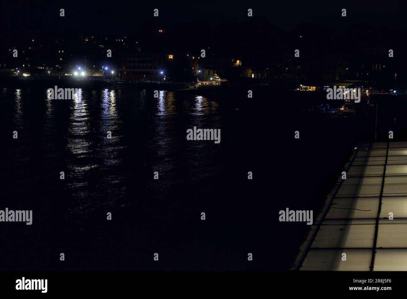 Town on a cliff by the sea at night seen from a beach afar Stock Photo ...