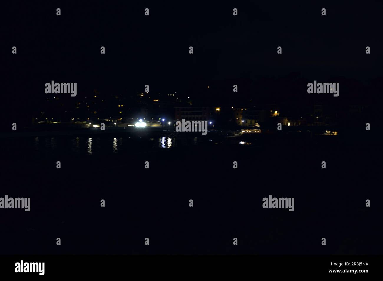 Town on a cliff by the sea at night seen from a beach afar Stock Photo ...