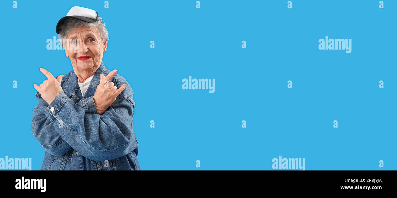 Stylish senior woman showing devil horns gesture on light blue ...