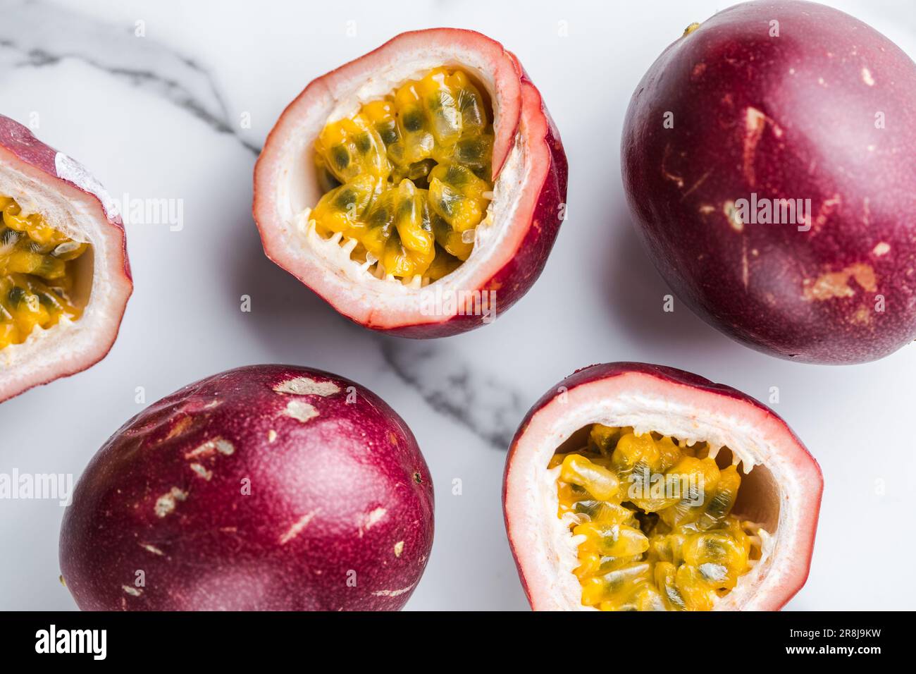 Ripe passion fruit, half and slice of fruit on a white marble ...
