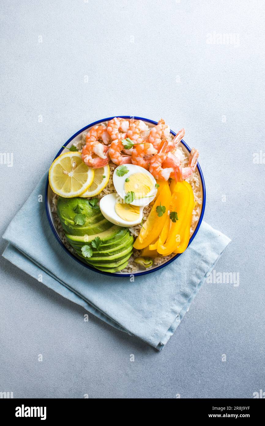 tropical bowl with avocado, prawns, rice, on light background. Healthy ...