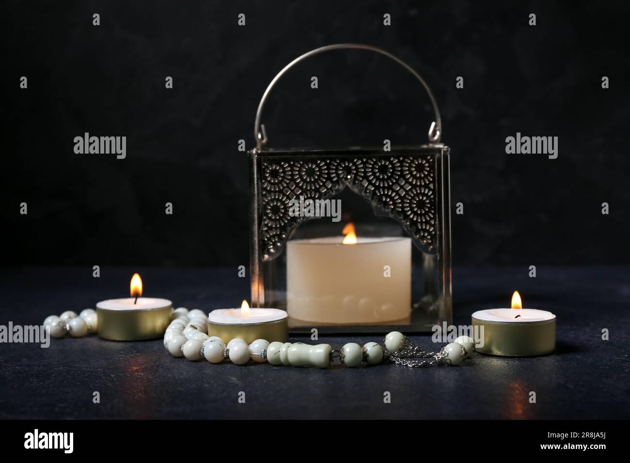 Muslim lamp with burning candles and prayer beads on dark background ...