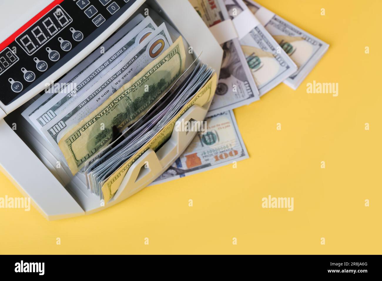 Modern cash counting machine with dollar banknotes on yellow background ...