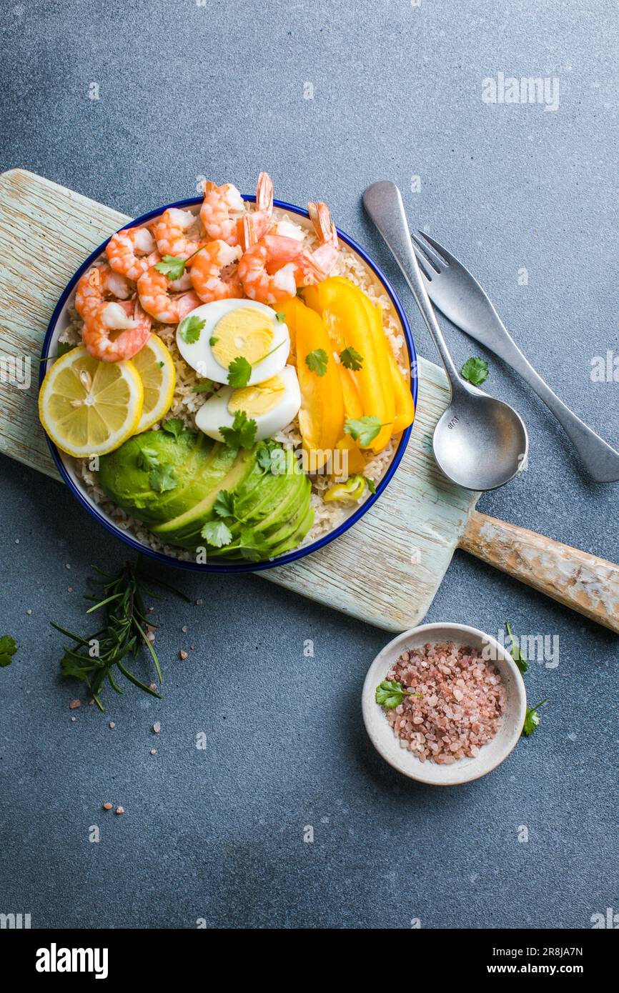 tropical bowl with avocado, prawns, rice, on light background. Healthy ...