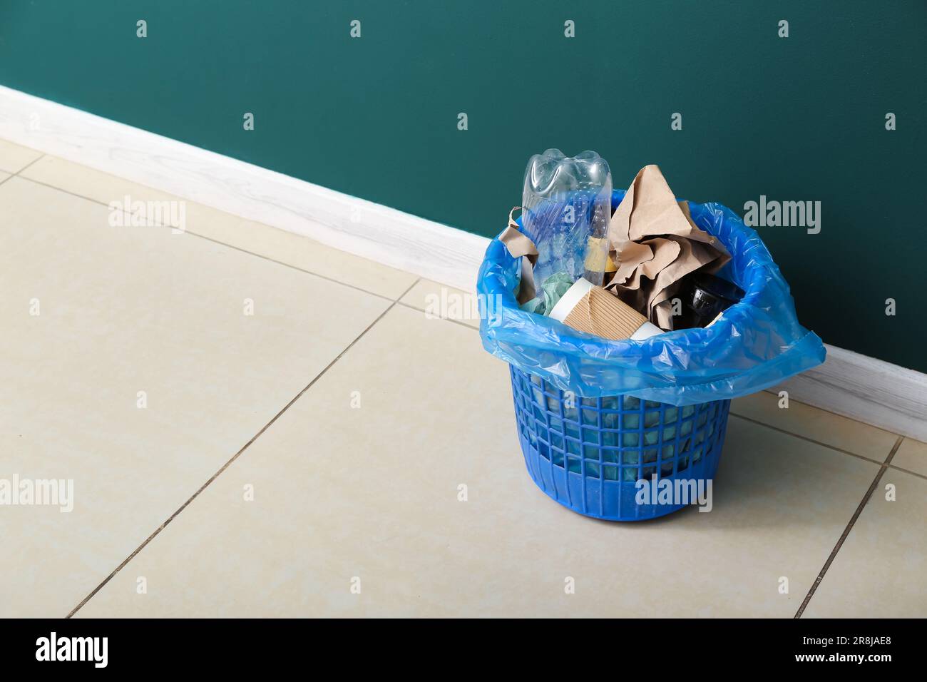 Trash bin with different garbage near green wall Stock Photo - Alamy
