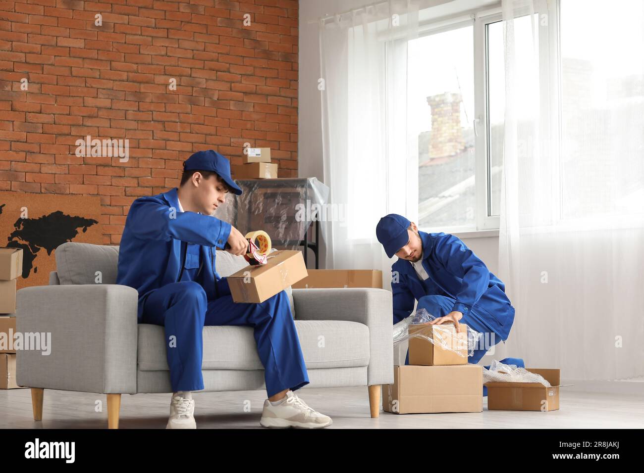 Male movers wrapping boxes in room Stock Photo - Alamy
