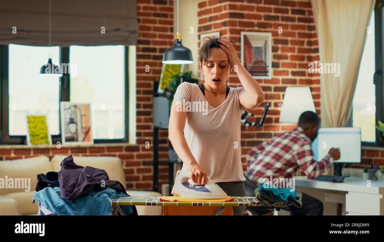 Depressed woman feeling tired of ironing washed clothes, stressed ...