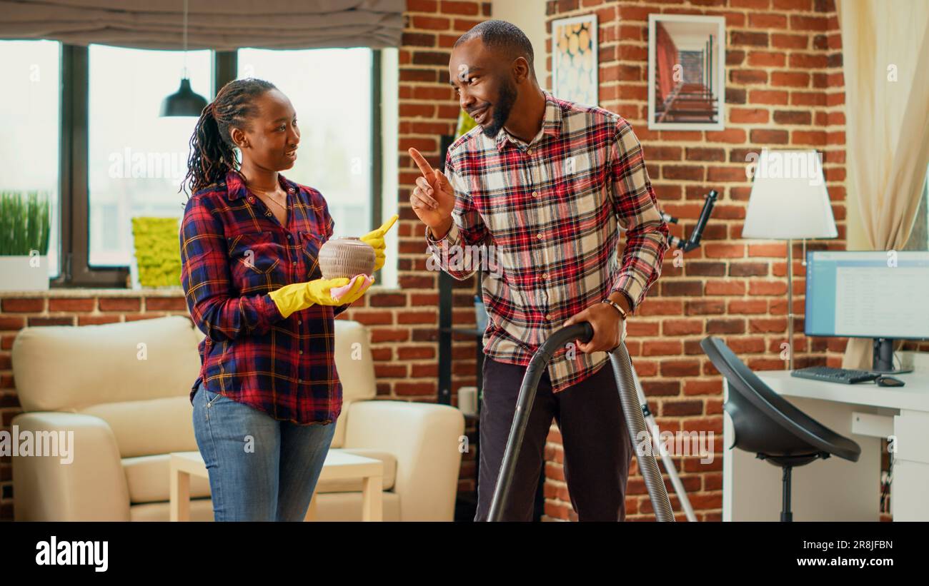 Life partners doing spring cleaning together in living room, focused ...