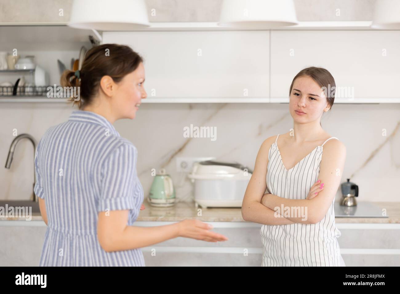 Kind middle-aged mother talking to young daughter in the kitchen Stock ...