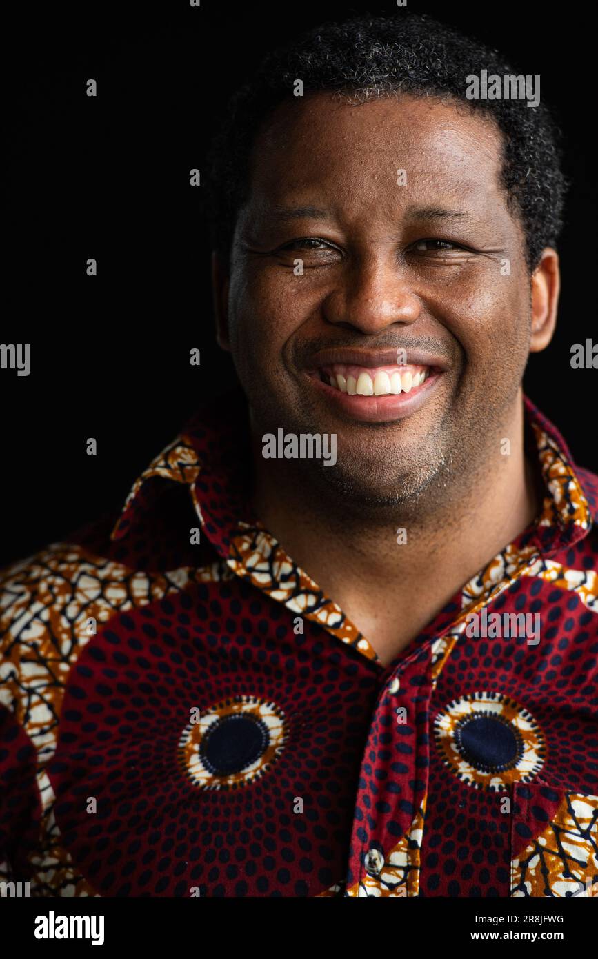 Portrait of handsome African man smiling against black background Stock ...