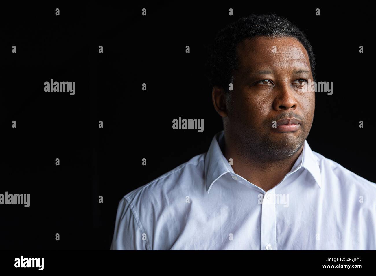 Portrait of handsome African man thinking against black background ...
