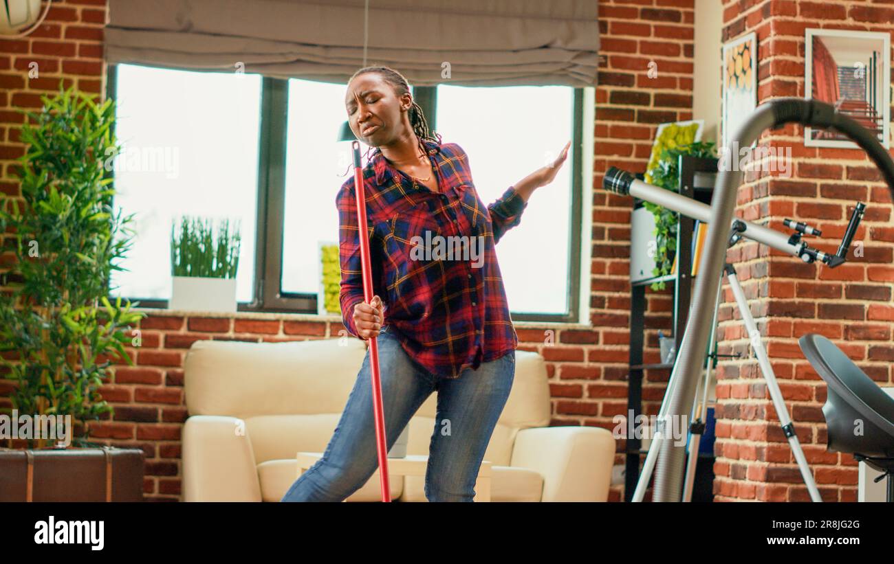 Female adult dancing and having fun cleaning household, listening to ...