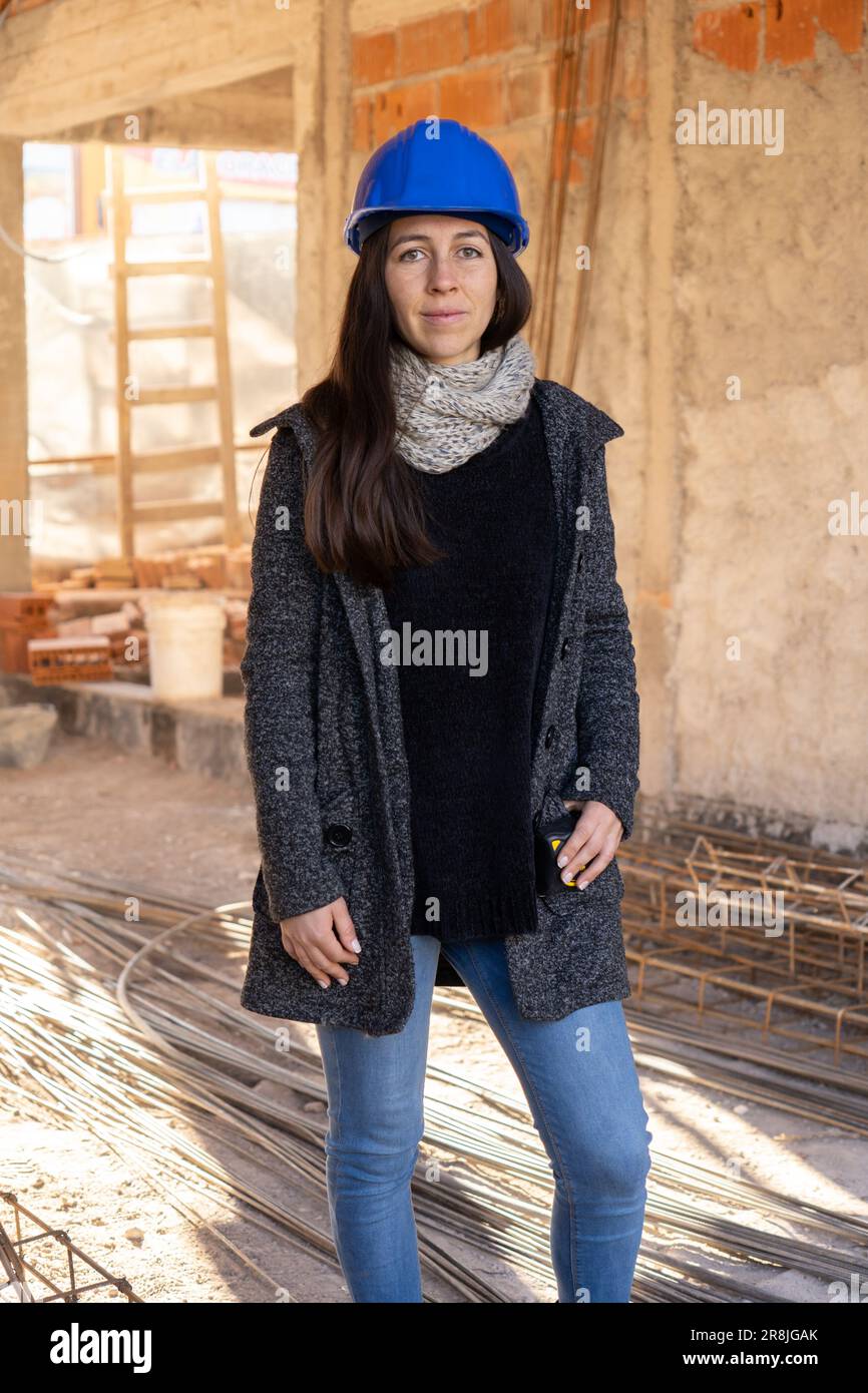 Vertical full-length portrait of female architect standing looking at ...