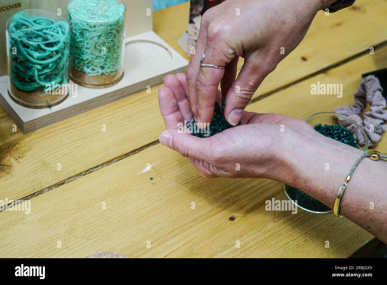 A person's hand seen holding recycled plastic pellets from abandoned ...