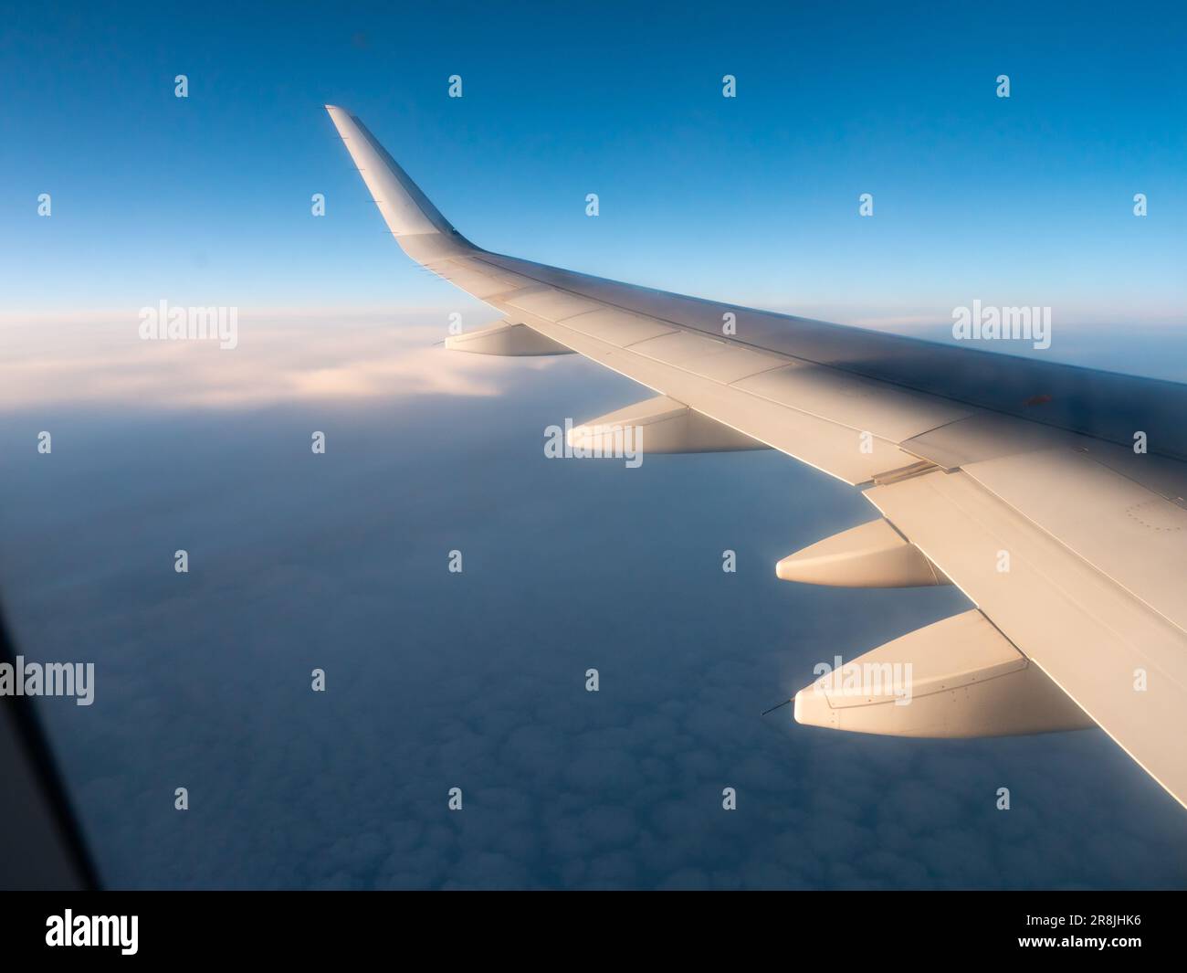 View from passenger window of wing of airplane flying in sky on sunny ...