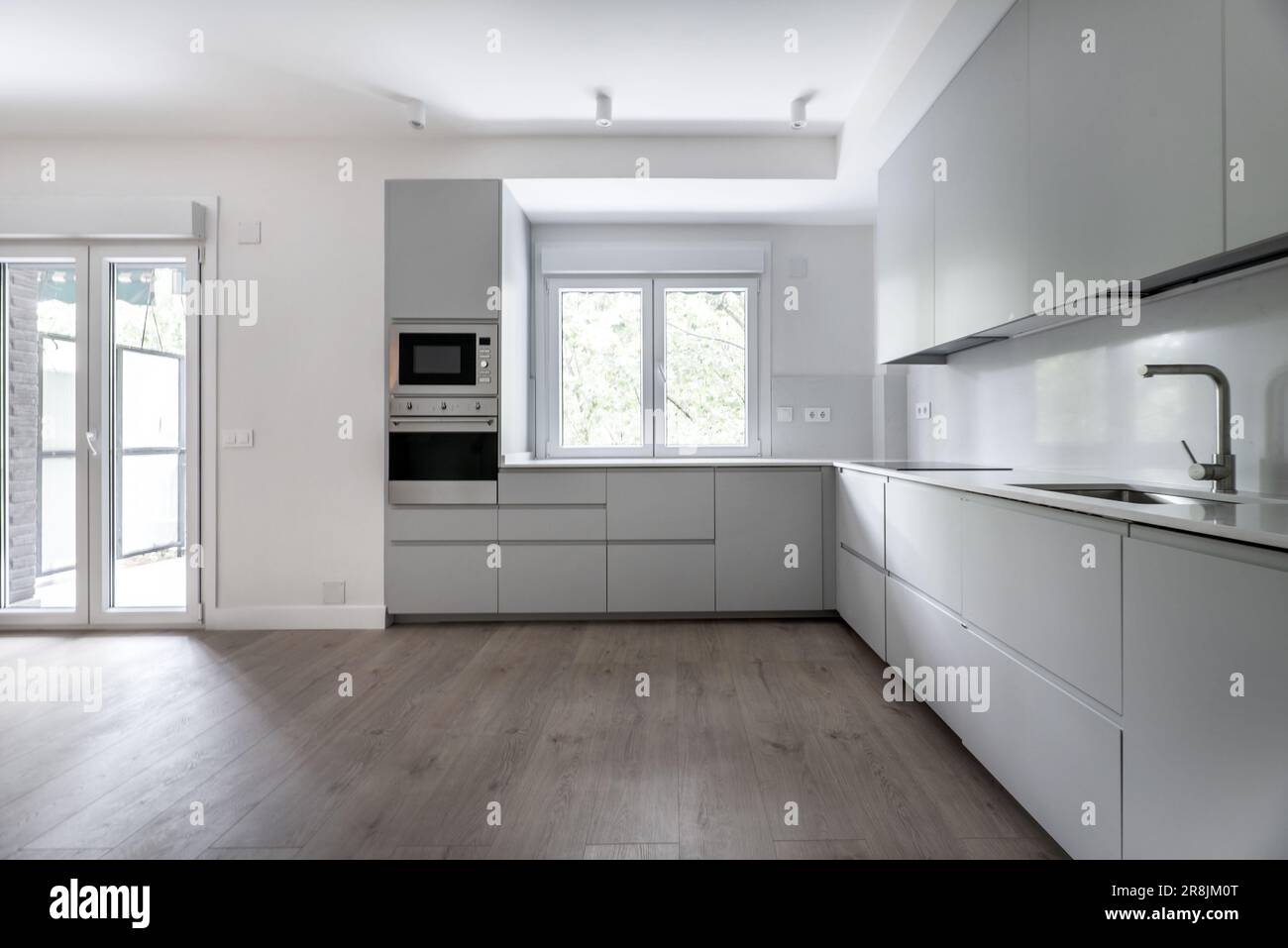 Corner of a newly fitted modern kitchen with gray handleless units and ...