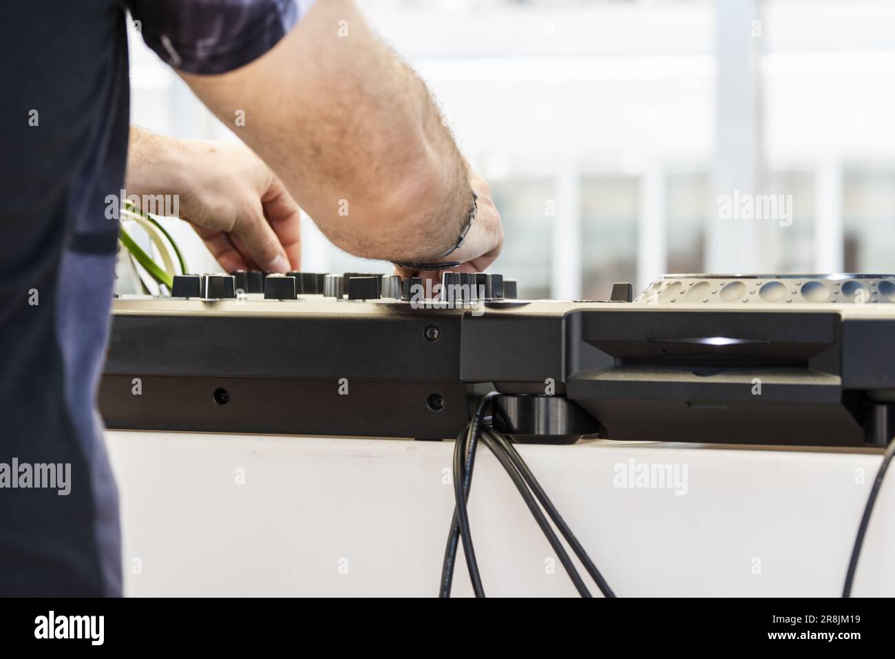 The arms of a dj playing with music on his mixing desk Stock Photo - Alamy