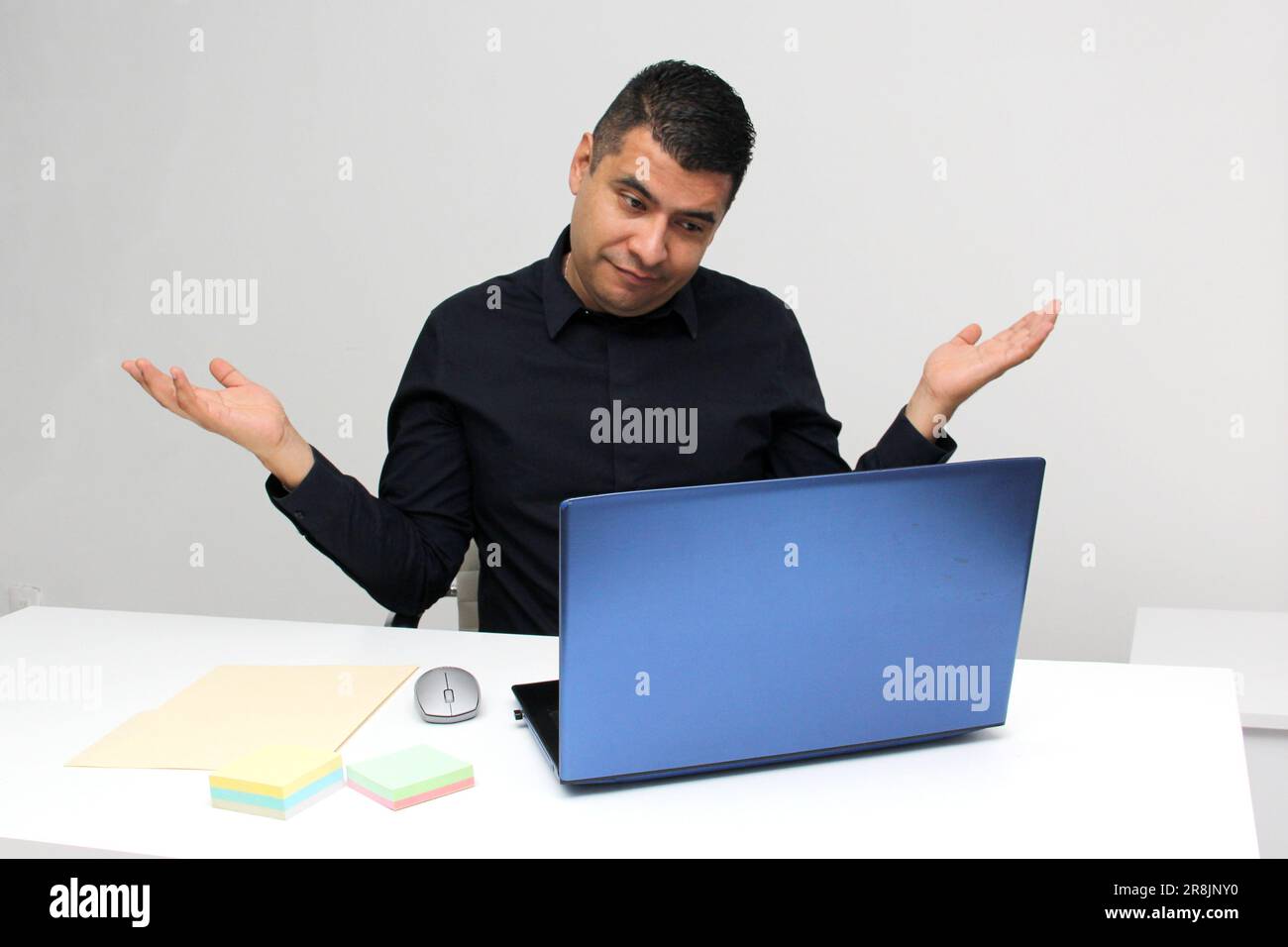 Dark-haired 40-year-old Latino man works in his office with his laptop ...