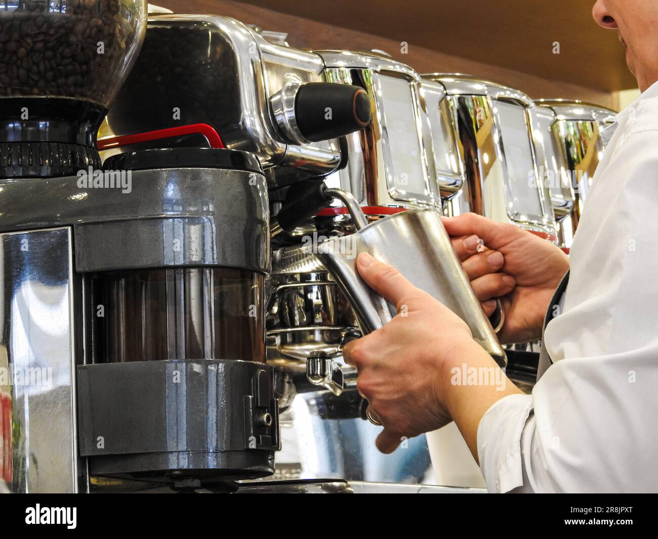 An authentic Italian barista skillfully froths milk with a traditional ...