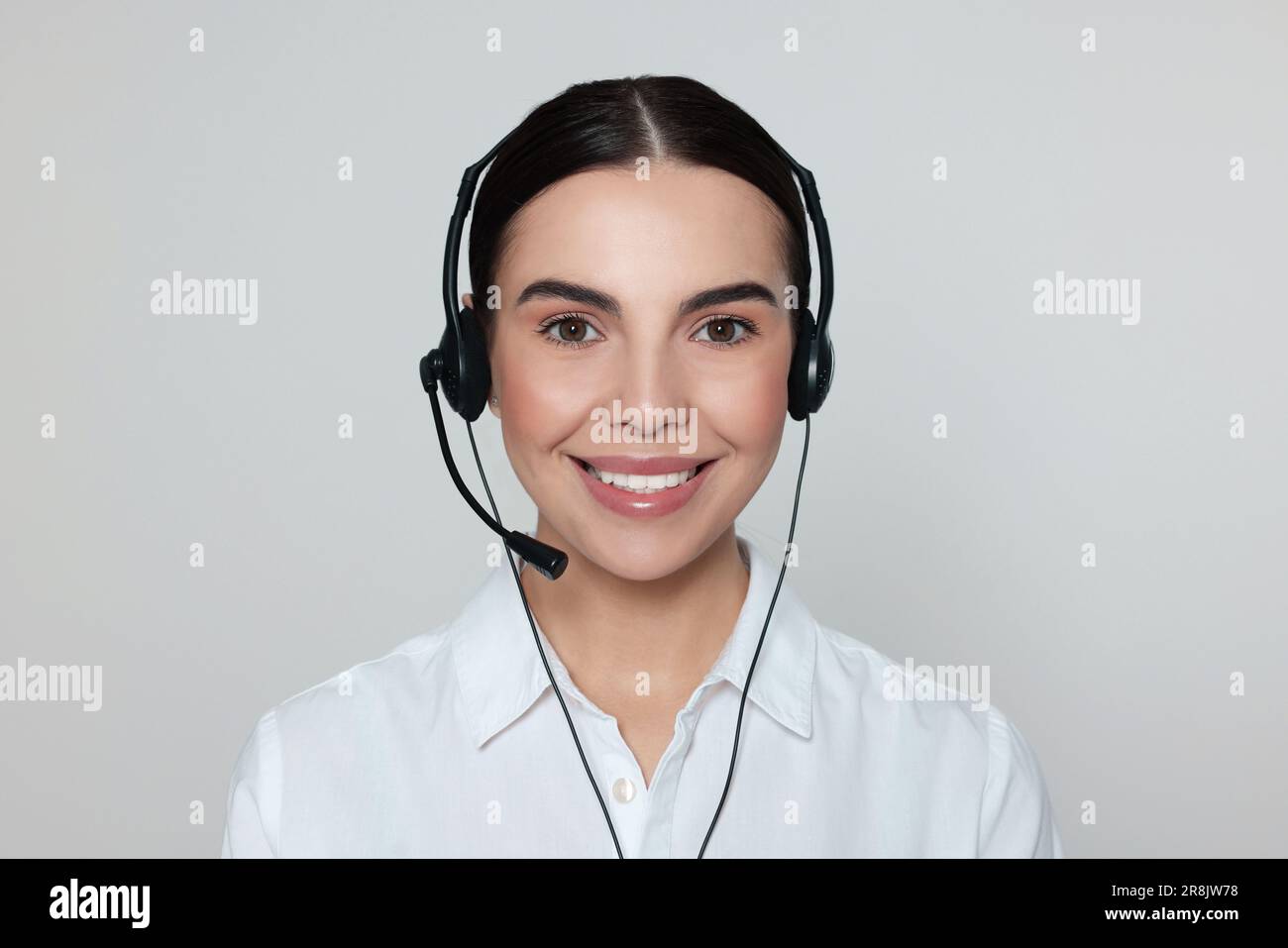 Hotline operator with modern headset on light grey background. Customer ...