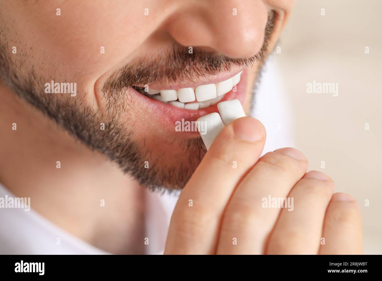 Man putting chewing gums into mouth on blurred background, closeup ...