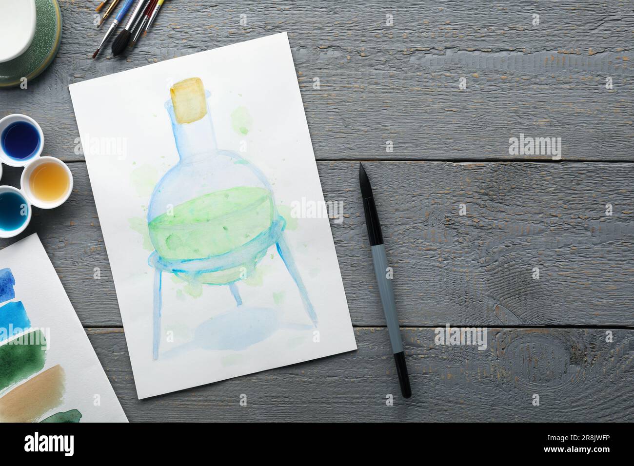 Flat lay composition with watercolor painting of flask and brushes on ...