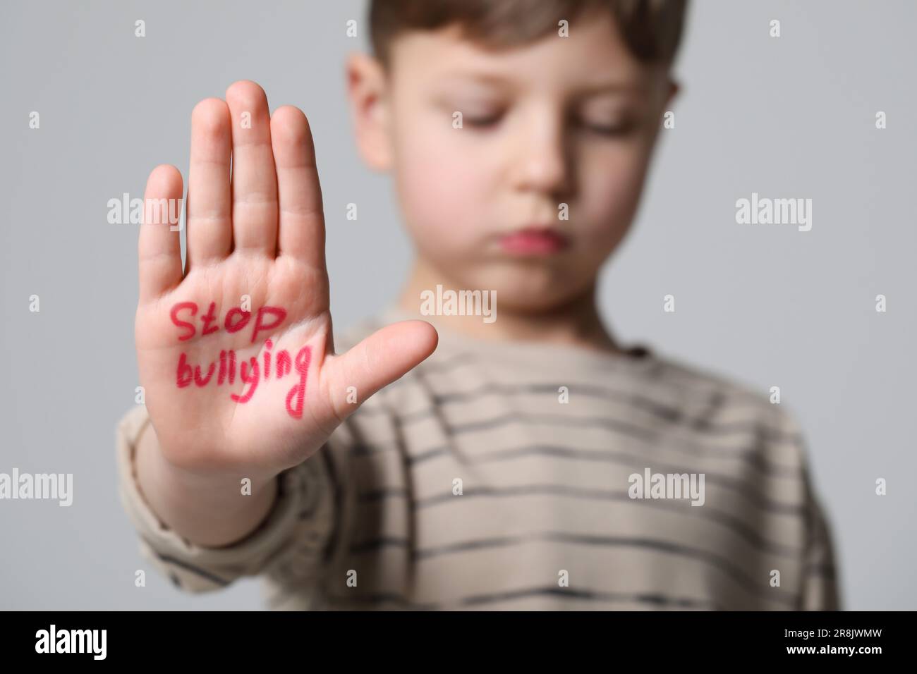Boy showing hand with phrase Stop Bullying on light grey background ...