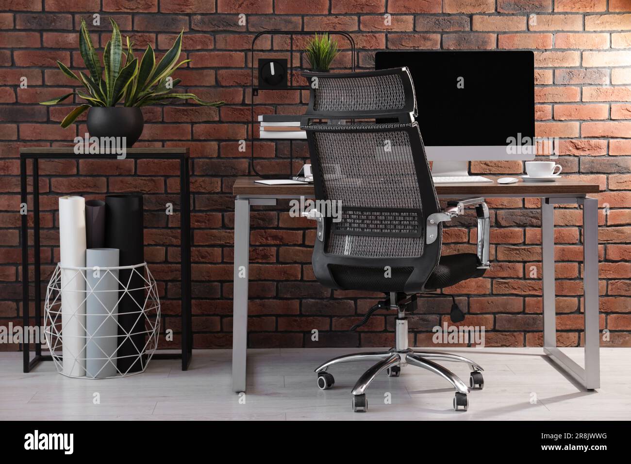 Cosy workspace with computer on desk, chair and potted plants near ...