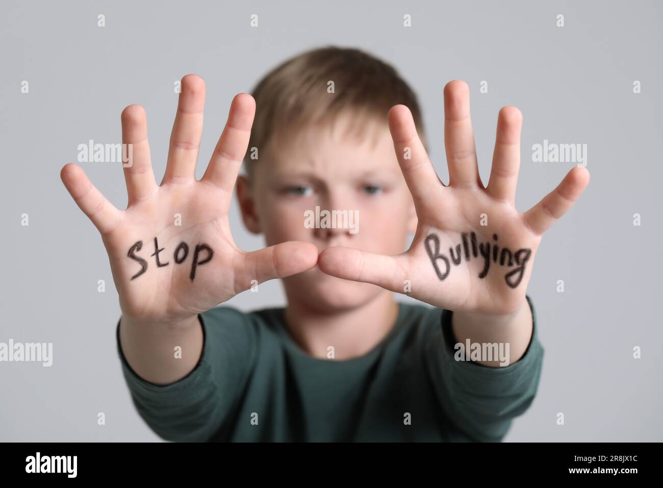 Boy showing hands with phrase Stop Bullying on light grey background ...