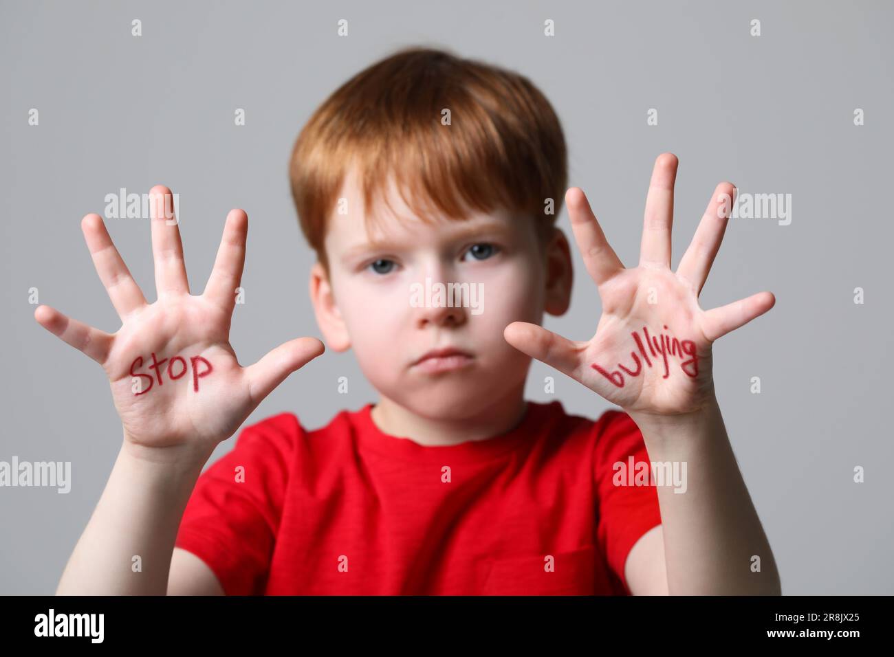 Boy showing hands with phrase Stop Bullying on light grey background ...