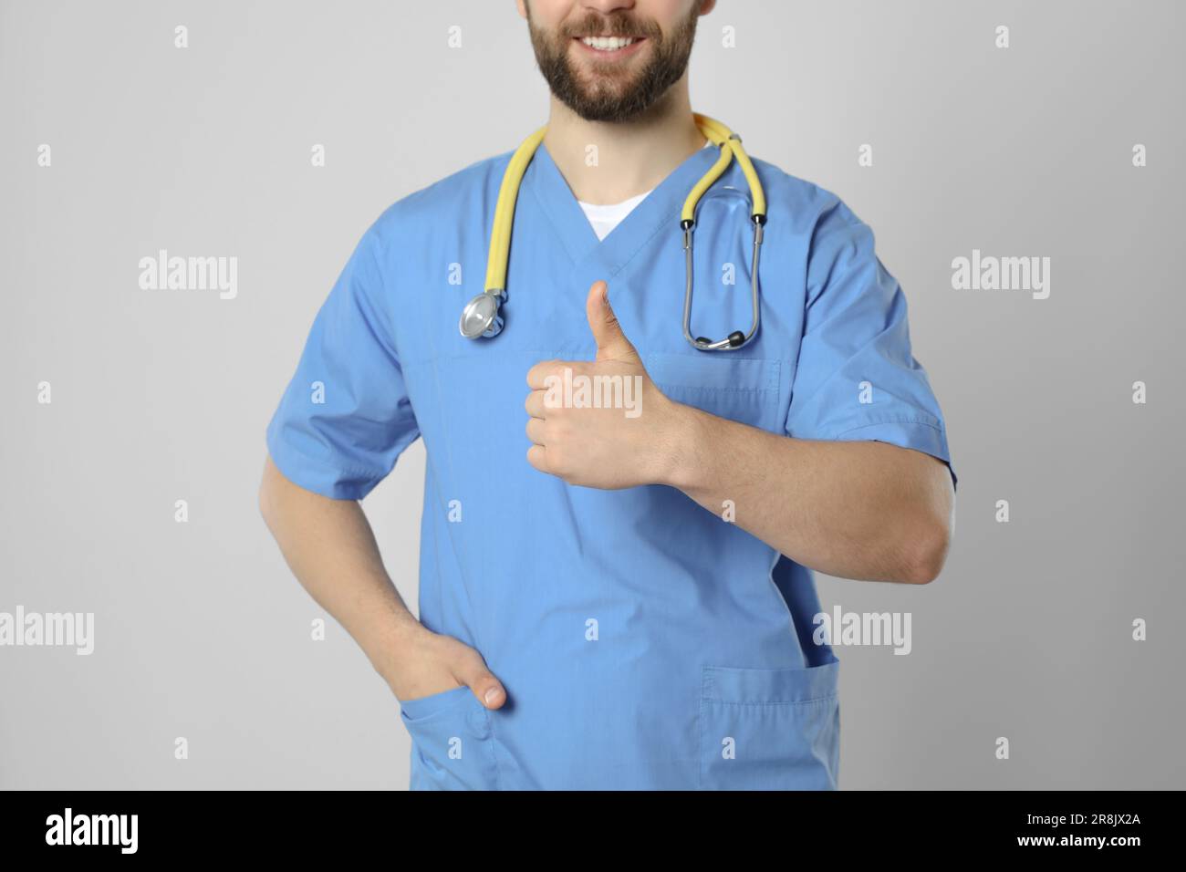 Doctor or medical assistant (male nurse) with stethoscope showing thumb ...