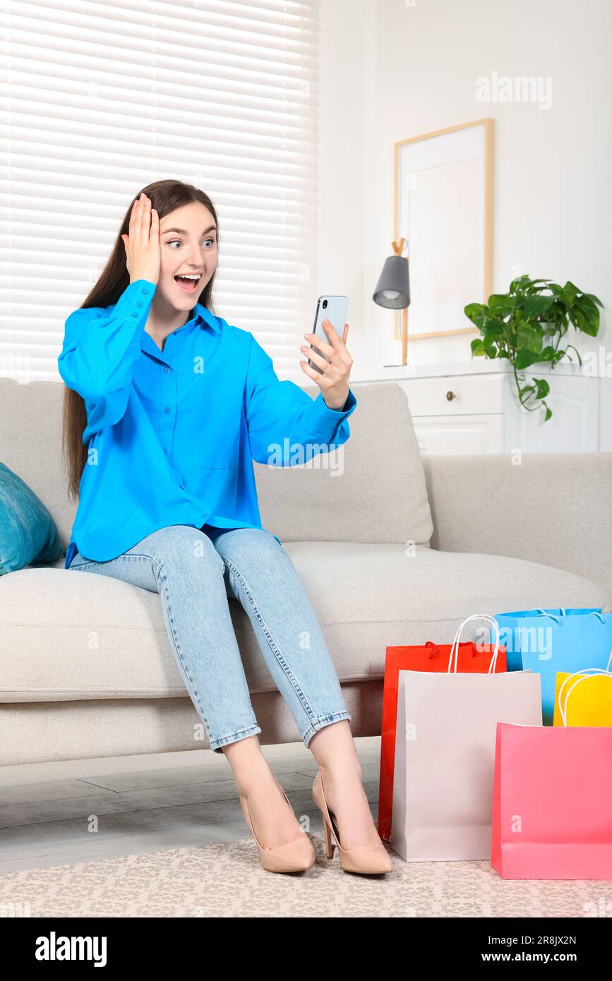 Special Promotion. Emotional woman with smartphone on sofa indoors ...