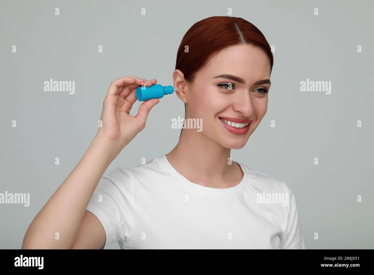 Woman using ear drops on light grey background Stock Photo - Alamy