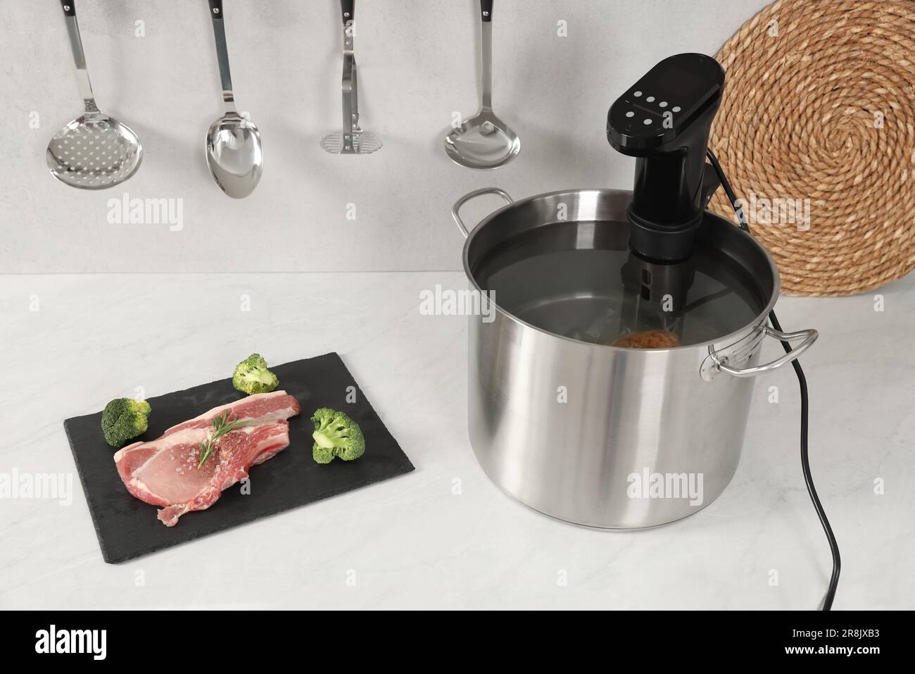 Pot with sous vide cooker and ingredients on table in kitchen. Thermal ...