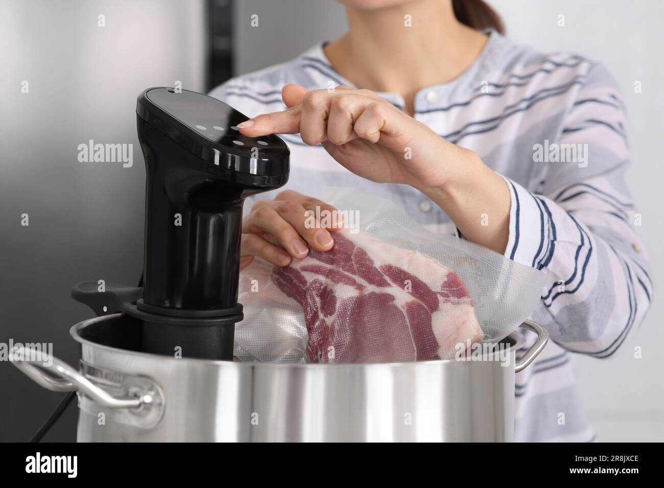 Woman putting vacuum packed meat into pot and using thermal immersion ...