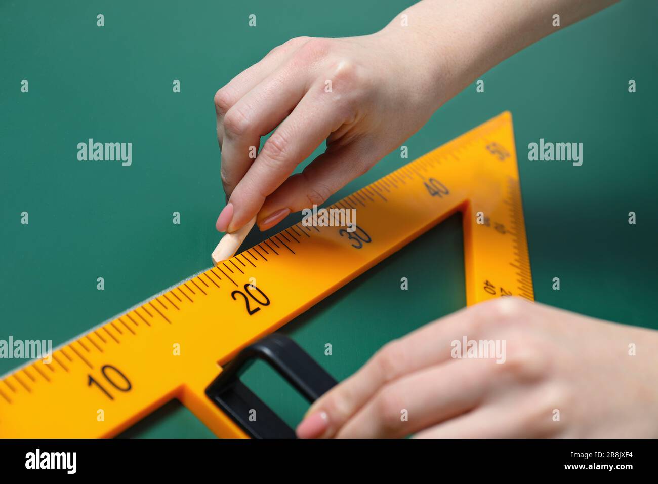 Woman drawing with chalk and triangle ruler on green board, closeup ...