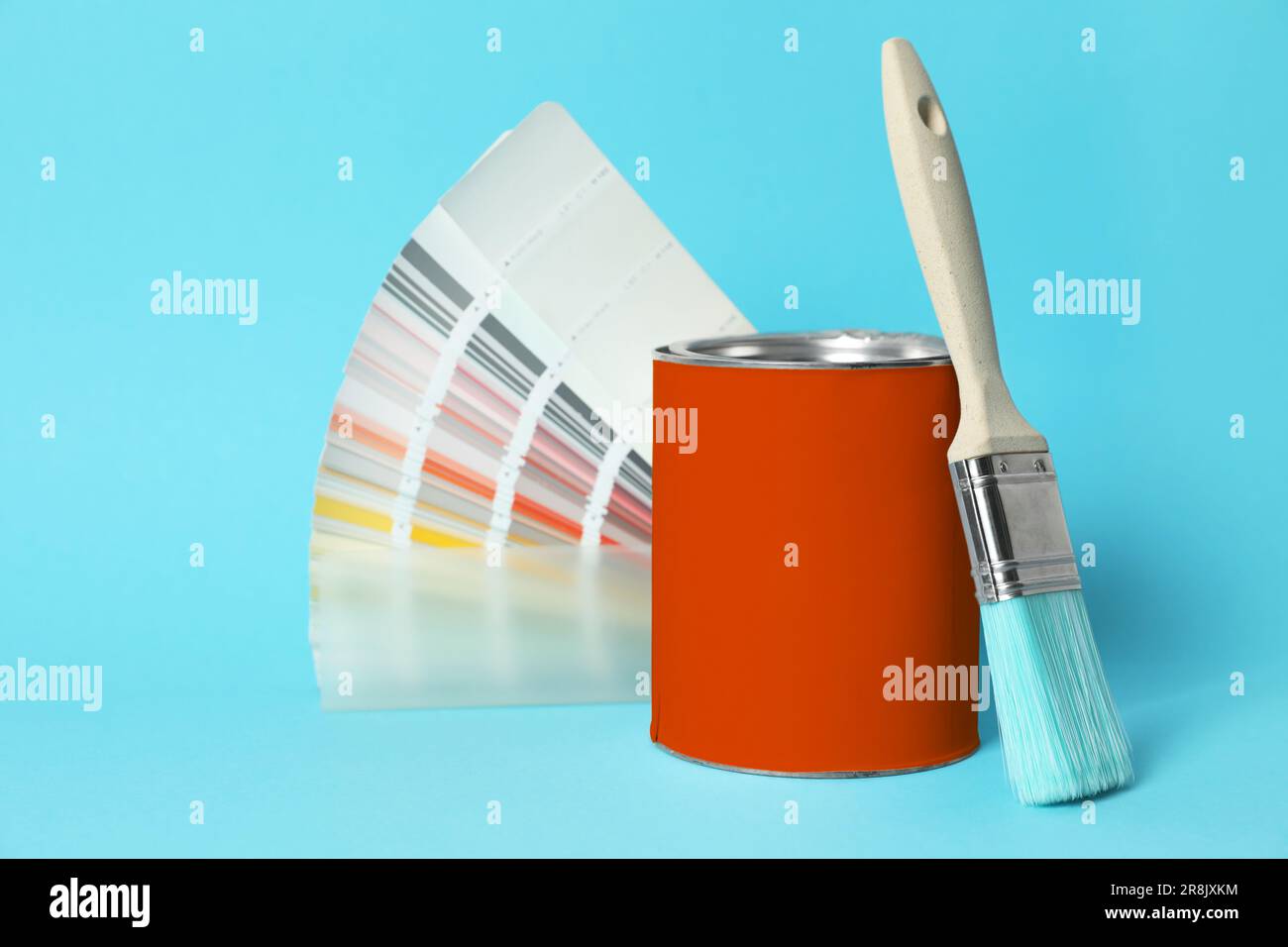 Can of orange paint, color palette samples and brush on turquoise ...